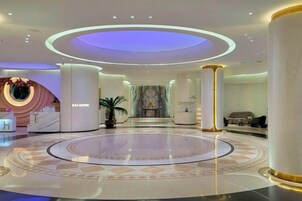 Um hall amplo com piso de mármore circular, balcão de recepção e área de estar.