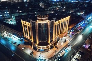 Um edifício alto com um letreiro grande do Traders Hotel no topo.