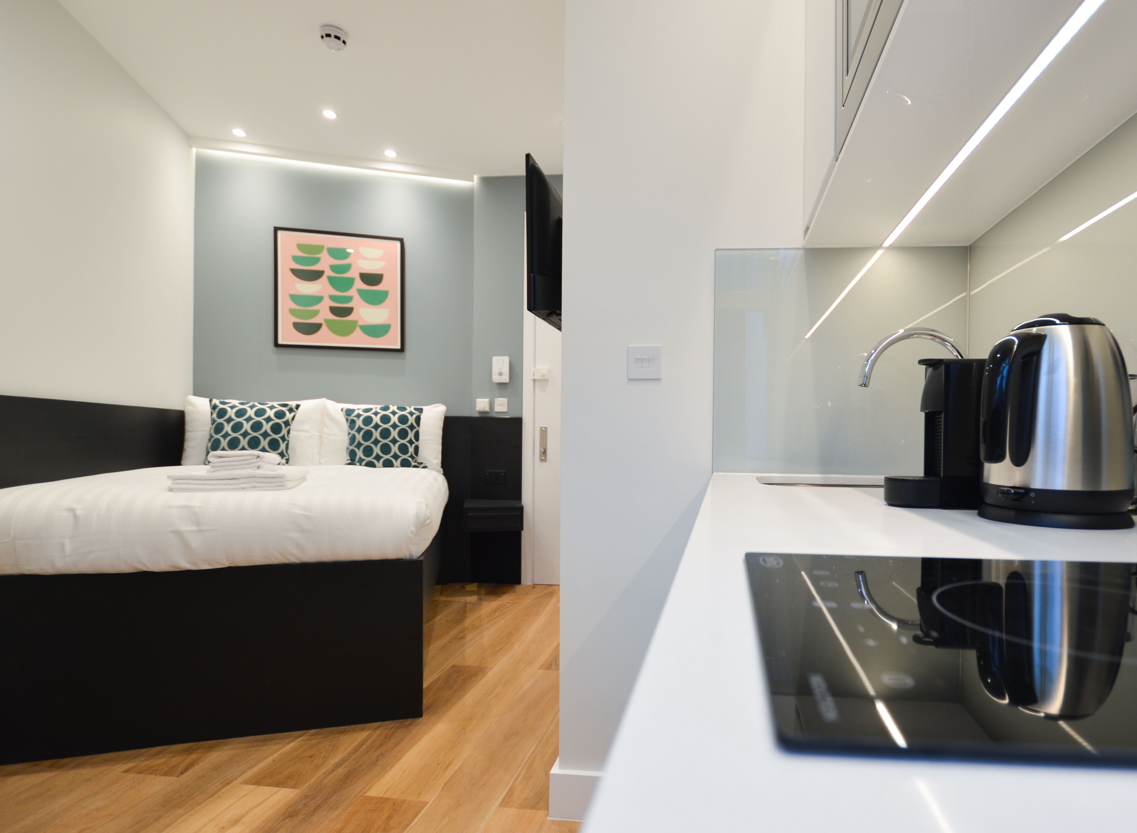 Quarto de hotel moderno com cama, cafeteira e televisão de tela plana.
