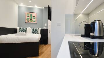 Quarto de hotel moderno com cama, cafeteira e televisão de tela plana.