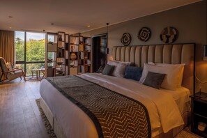Quarto moderno com cama grande, estante embutida e vista para o verde lá fora.