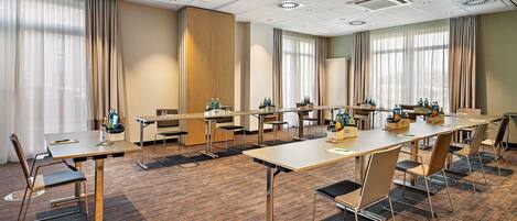 Uma sala de conferência com várias mesas e cadeiras, equipada com placas de identificação, garrafas de água e copos.