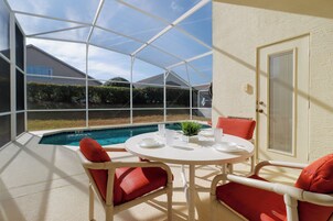 Um pátio coberto com piscina, área de estar ao ar livre e vista para uma casa e paisagem.