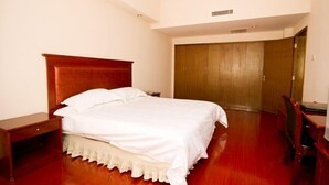 Quarto com cama de madeira, mesa de cabeceira, escrivaninha e guarda-roupa.
