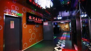 Um corredor bem iluminado, com um letreiro de neon, paredes estampadas e um design de chão colorido.