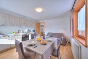 Uma cozinha moderna com área de jantar, armários de madeira e uma janela com cortinas.