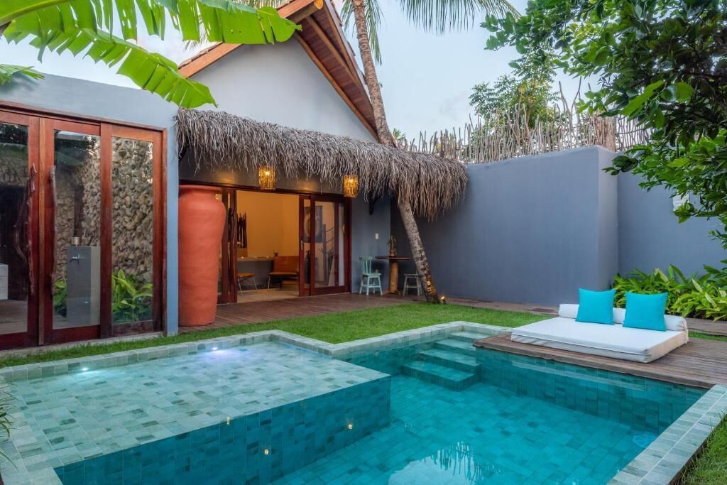 Uma villa moderna com piscina, telhado de palha e área de pátio com mobiliário de exterior.