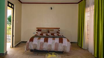 Quarto com cama, janela com cortinas verdes e porta que dá para o exterior.