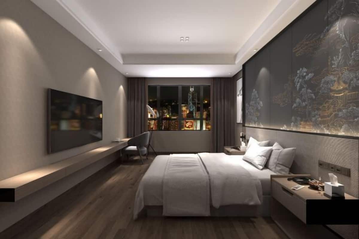 Quarto moderno com uma cama grande, TV na parede e janela com vista para as luzes da cidade.