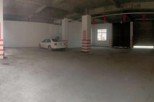 Uma garagem de estacionamento com um carro branco estacionado perto de um pilar, uma janela e uma porta.