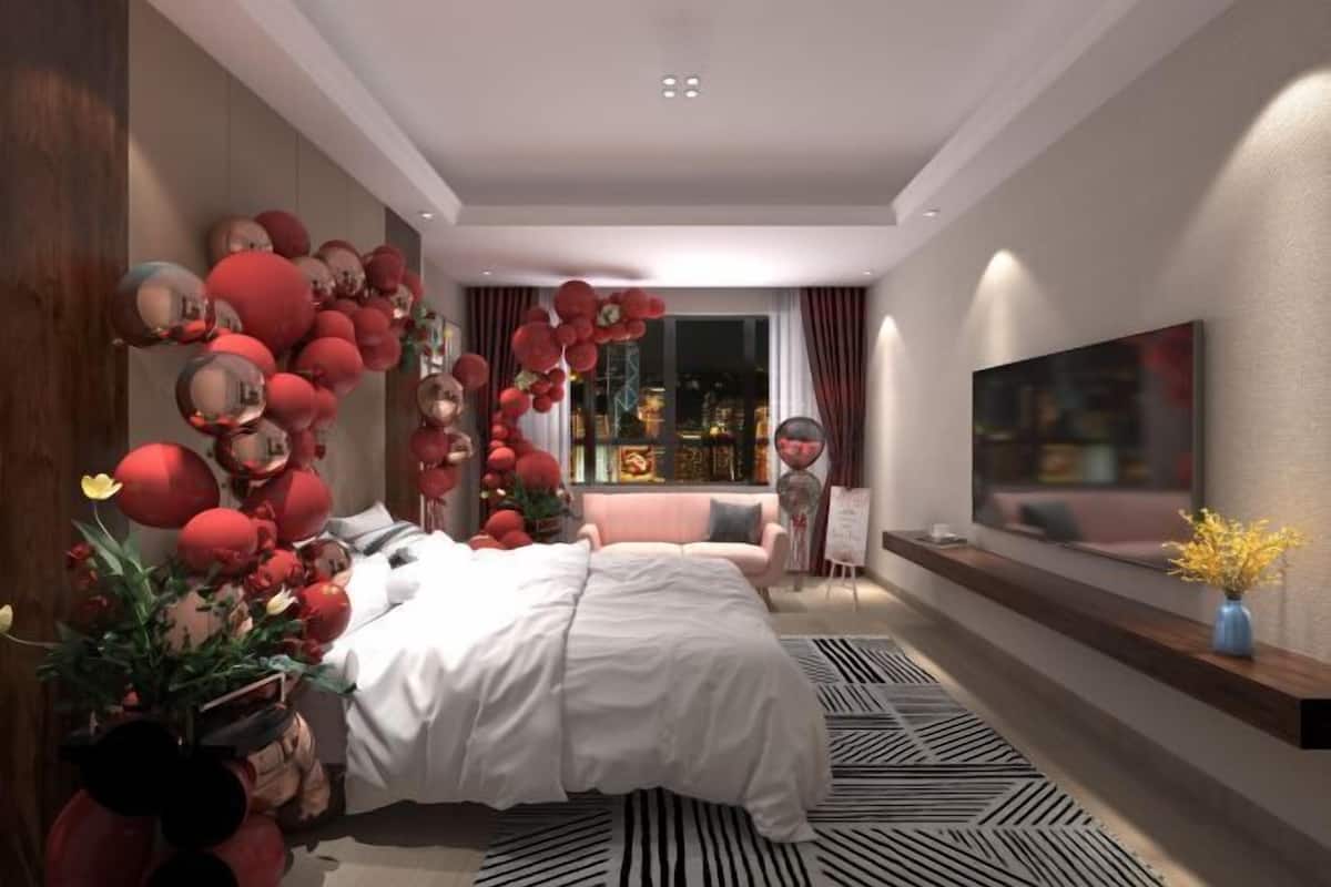 Quarto moderno com uma cama grande, uma TV fixada na parede e um arranjo decorativo de esferas vermelhas.