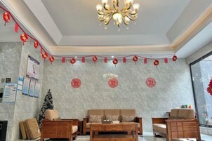 Um saguão de hotel com lustre, área de estar e elementos decorativos nas paredes.