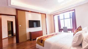 Quarto de hotel com uma cama grande, televisão de tela plana na parede, guarda-roupa de madeira e uma janela com cortinas.