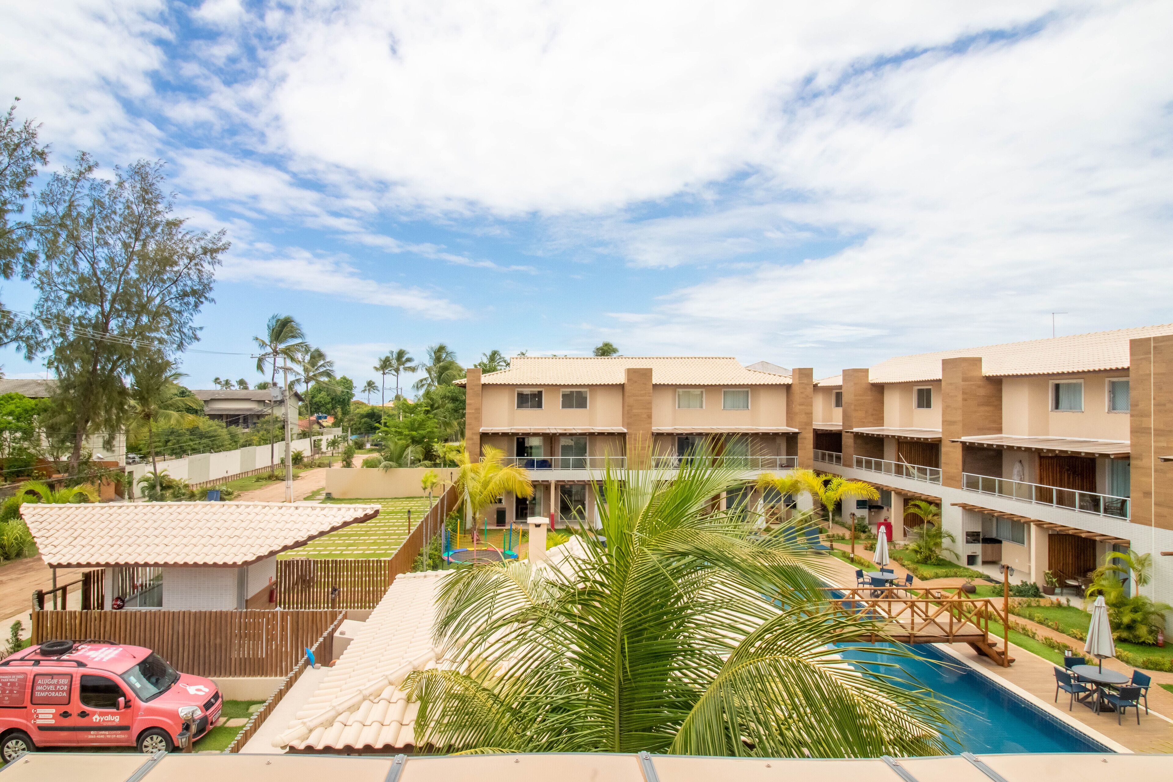 Um hotel com vários andares, piscina e área de jardim cercada.