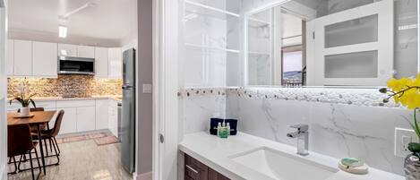 Cozinha moderna com armários brancos, painel de backsplash de tijolos e um espaço de refeições com mesa e cadeiras.