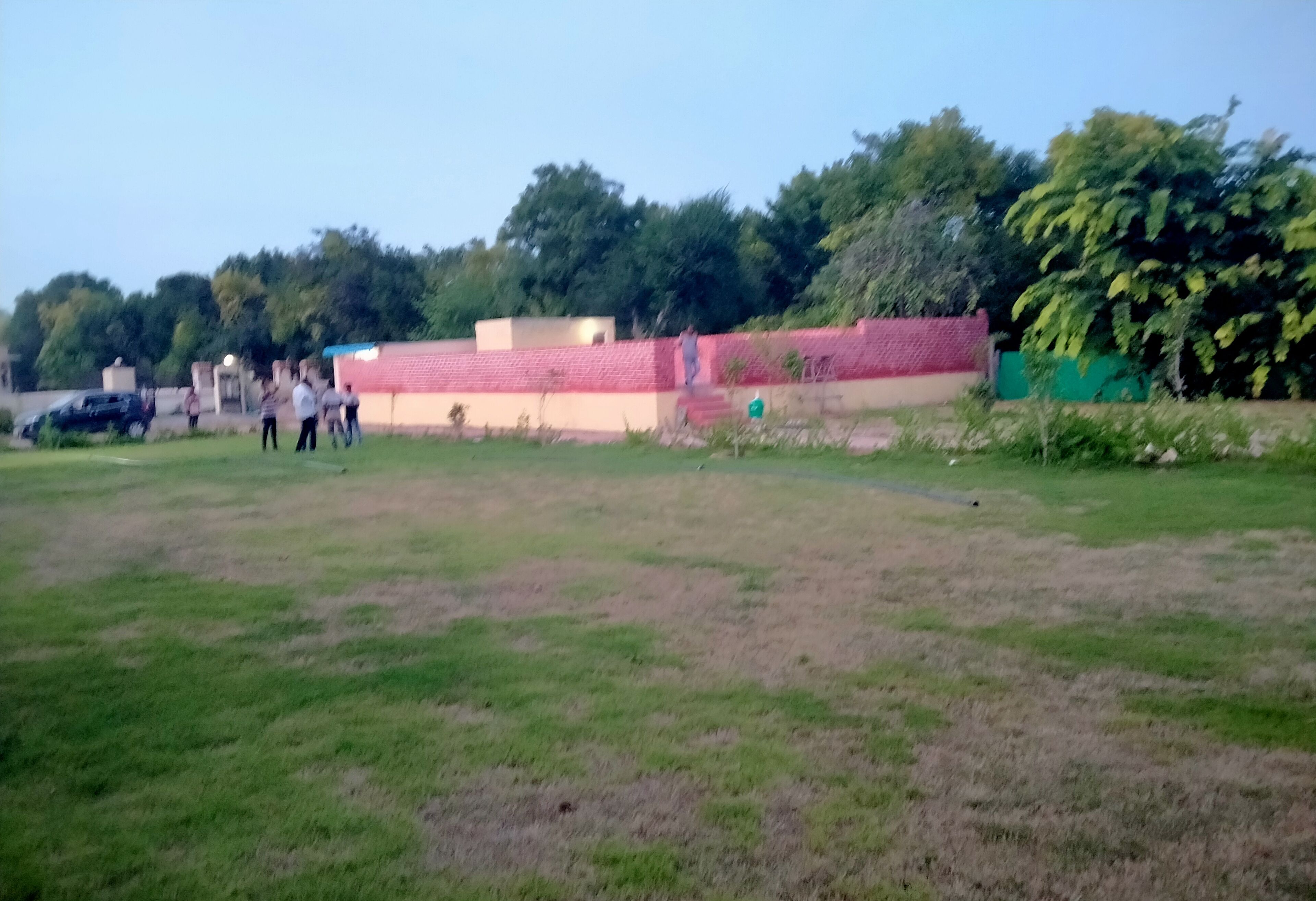 Um campo gramado com um edifício ao fundo.