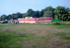 Um campo gramado com um edifício ao fundo.