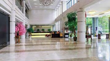 Um hall amplo com balcão de recepção, área de estar e grandes janelas que permitem entrada de luz natural.