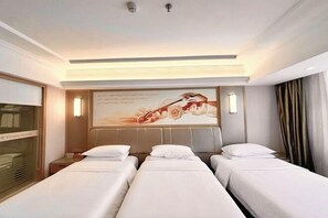 Quarto de hotel com três camas de solteiro, um grande mural na parede, frigobar e janela com cortinas.
