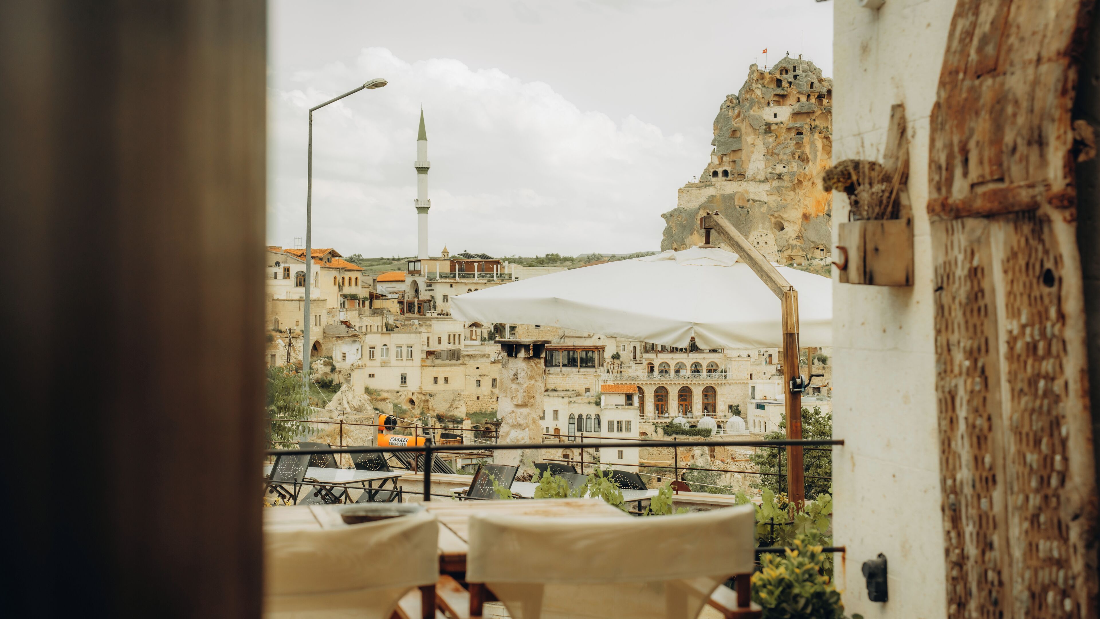 Vista de um horizonte urbano com edifícios históricos, um minarete e uma estrutura em forma de tenda branca.