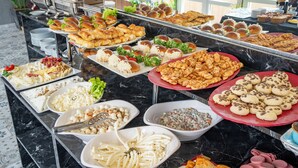 Buffet com diversos alimentos, incluindo sanduíches, saladas e sobremesas.