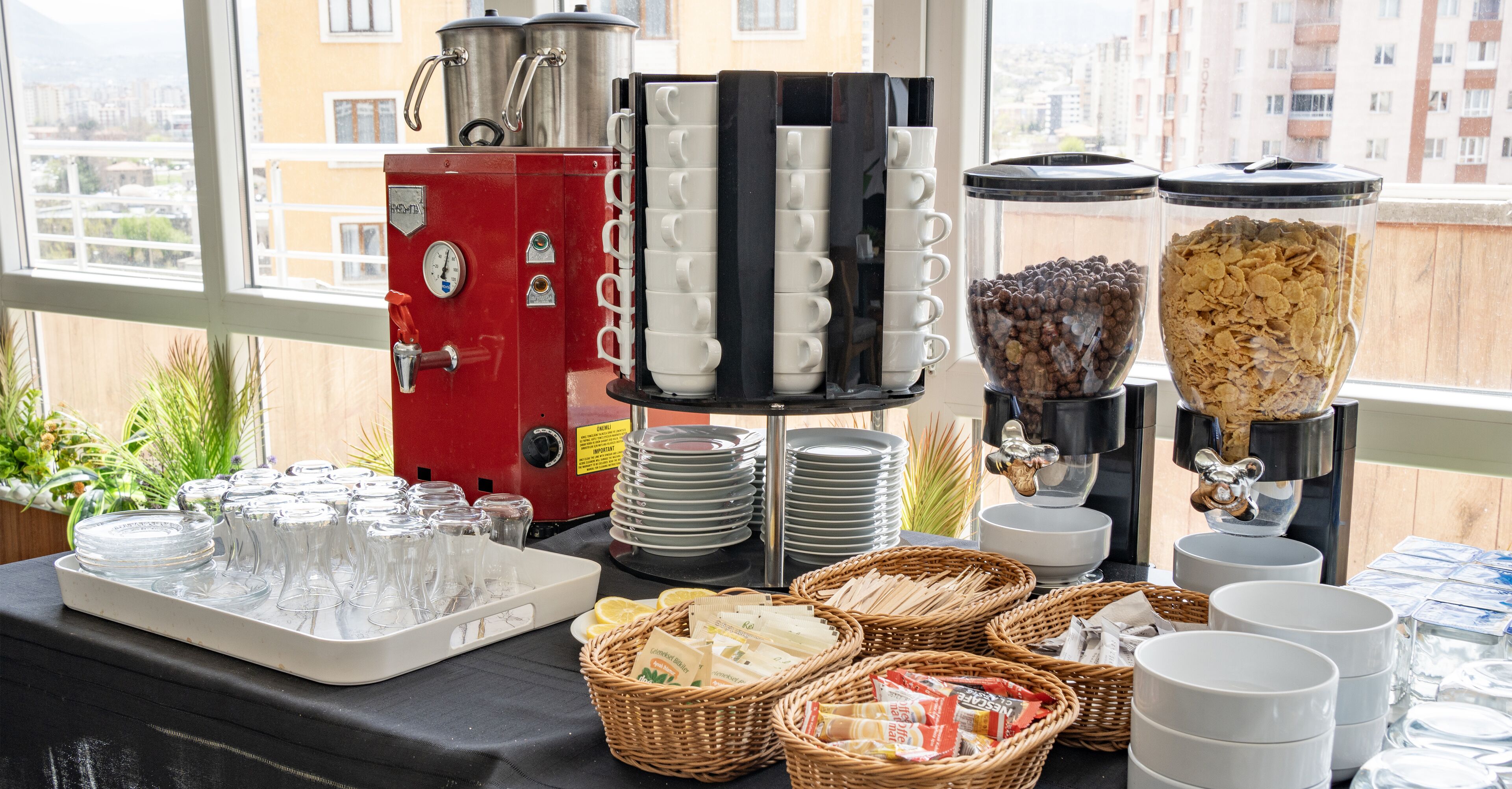 Disposição de buffet com máquinas de café, xícaras e recipientes de comida.