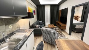 Quarto de hotel compacto com cozinha americana, sofá, mesa de jantar e cama.