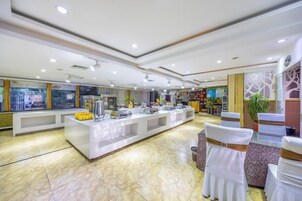 Um hall de hotel com balcão de recepção, área de estar e uma grande janela.