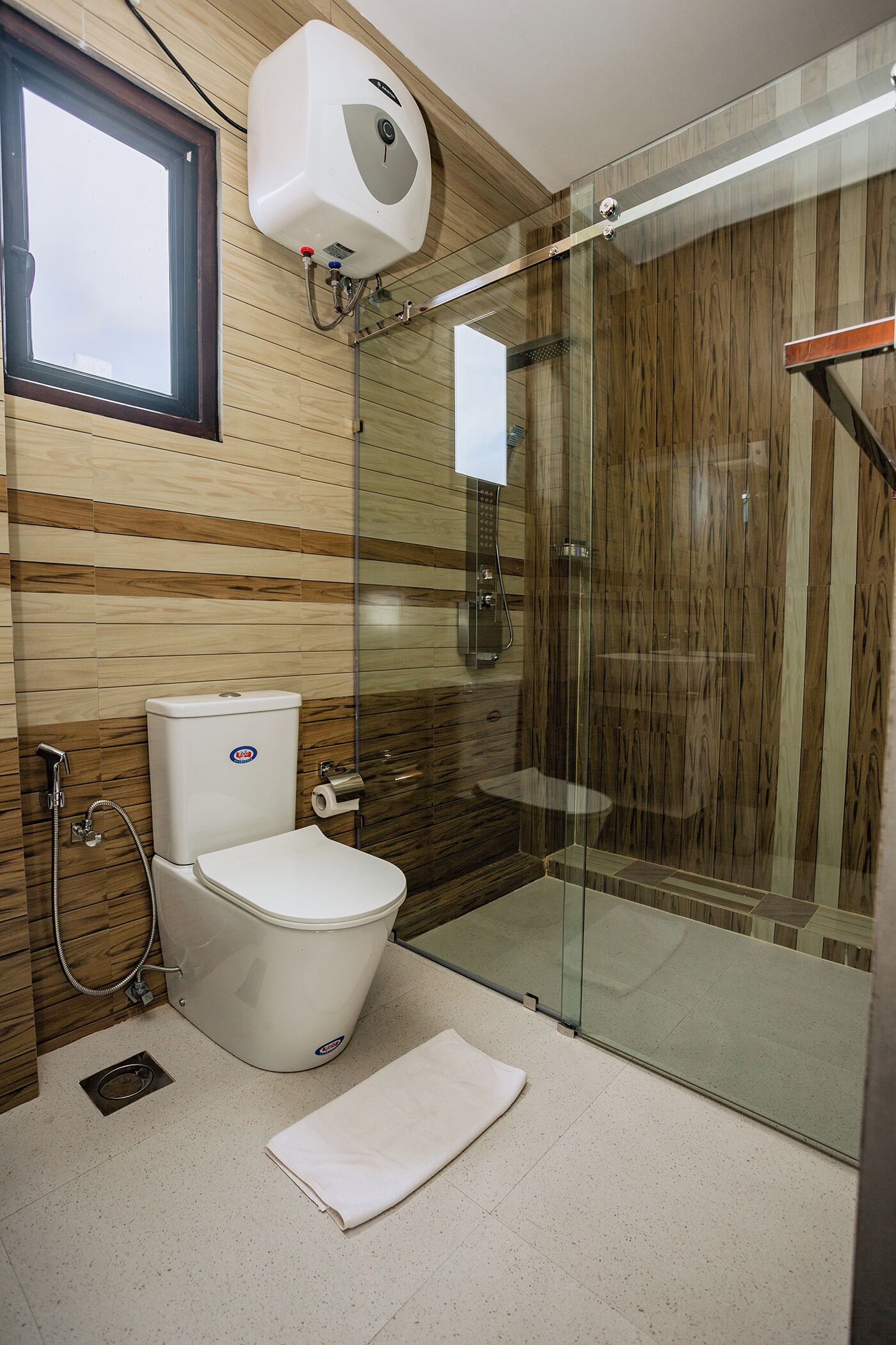 Uma casa de banho moderna com sanita, cabine de duche em vidro e painel de parede em madeira.