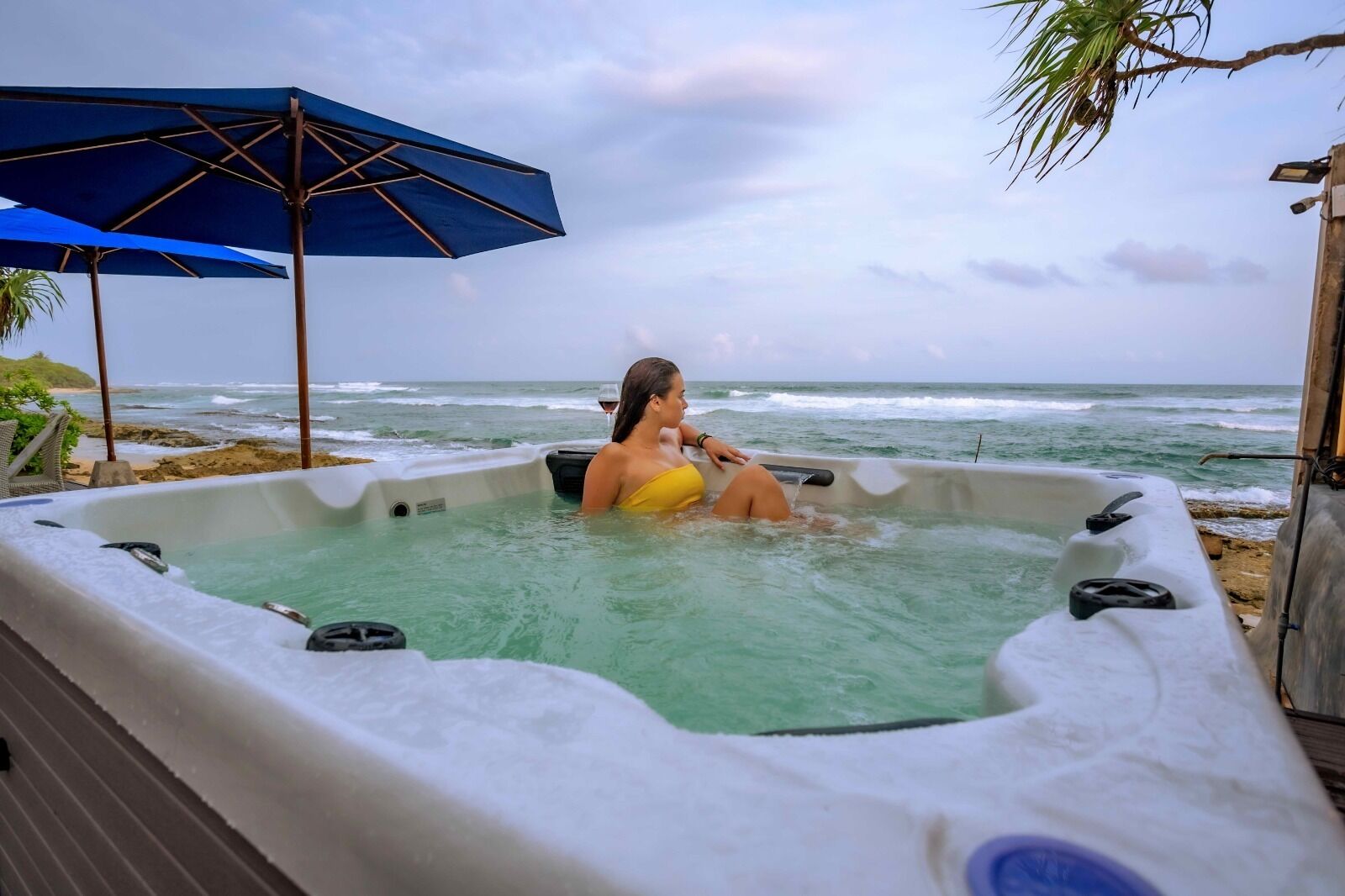 Uma pessoa relaxando em uma banheira de hidromassagem com vista para o oceano.