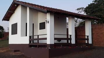 Um pequeno edifício térreo com telhado de cerâmica e varanda. Apresenta um design simples e funcional, com telhado plano e pequena área de varanda frontal.