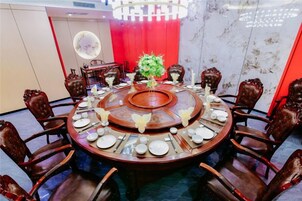 Uma mesa de jantar redonda com cadeiras, um arranjo floral central e um lustre.