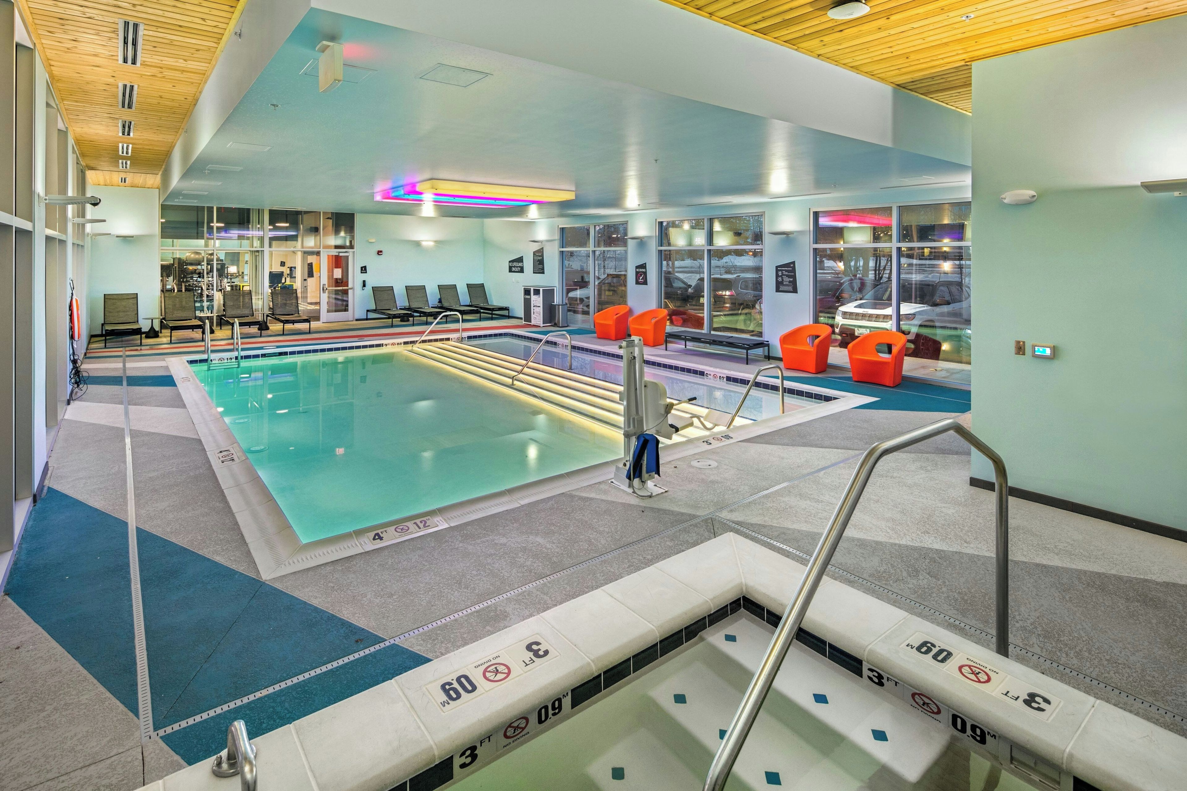 Uma área de piscina com trampolim, espreguiçadeiras e vestiários.