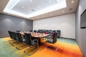 Uma sala de conferências com teto alto, uma mesa grande e várias cadeiras.