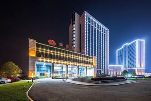 Um hotel com fachada moderna, entrada central e área de estacionamento.