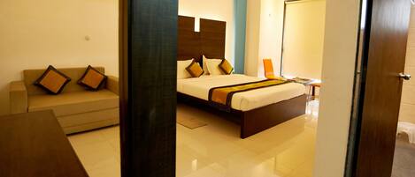 Quarto de hotel com cama, sofá e escrivaninha.