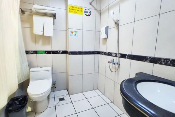 Um banheiro pequeno com azulejos, vaso sanitário, pia e chuveiro.
