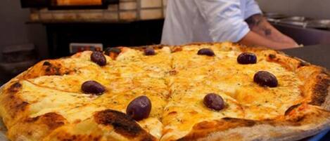 Uma pizza grande com azeitonas em uma bandeja de metal.
