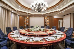 Uma mesa de conferência redonda com cadeiras, um arranjo floral e um candelabro.