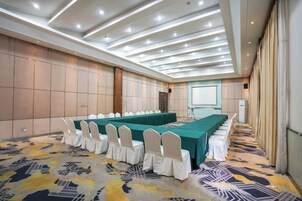 Uma sala de conferência com uma mesa comprida, cadeiras brancas e um projetor.