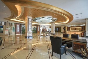 Um hall amplo com uma fonte central, balcão de recepção e design de teto moderno.