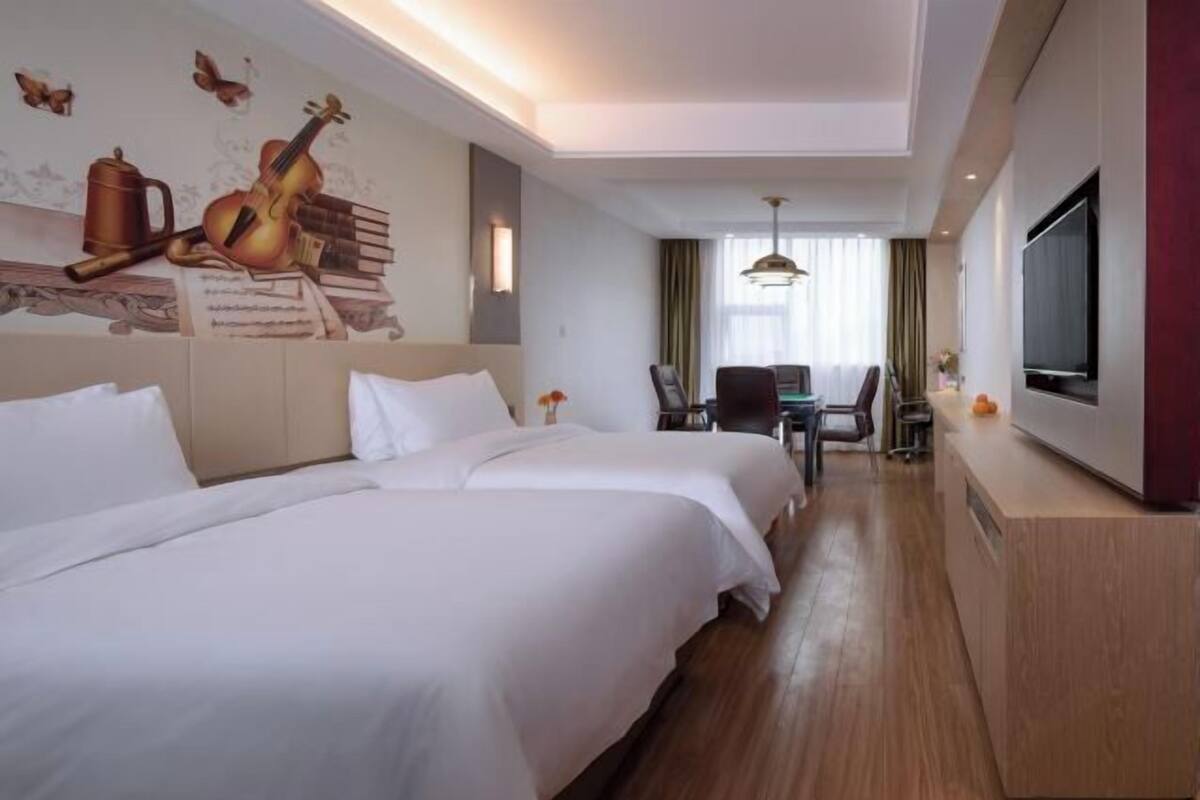 Quarto de hotel com duas camas, televisão, escrivaninha e um mural de instrumentos musicais.