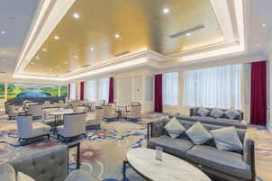Um amplo saguão de hotel com área de estar espaçosa, vista para a piscina e design de teto moderno.