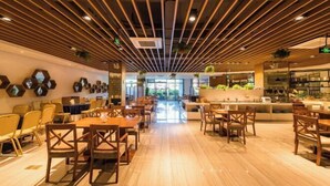 Um restaurante amplo com painéis de madeira no teto e um corredor central.