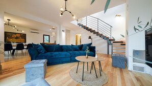 Uma sala de estar moderna com um sofá azul, uma mesa de centro redonda e uma escada.