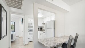Uma cozinha moderna com armários brancos, bancada de granito e geladeira embutida.