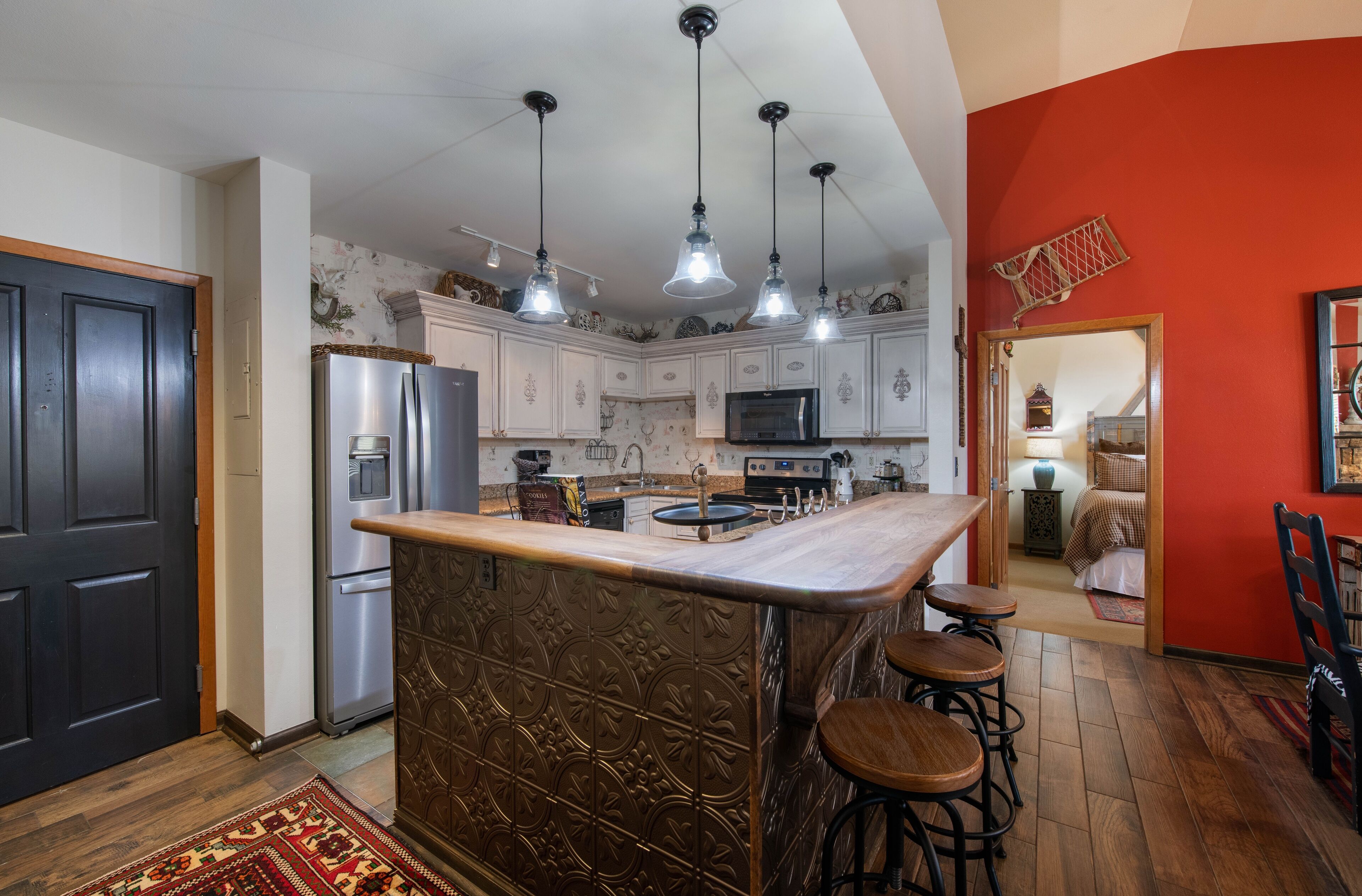 Cozinha com ilha central, banquetas e luminárias pendentes.