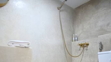 Casa de banho com chuveiro, sanita e porta-toalhas.