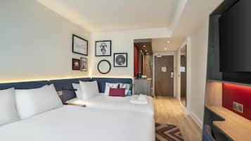 Quarto de hotel com uma cama grande, televisão e parede com fotografias emolduradas.