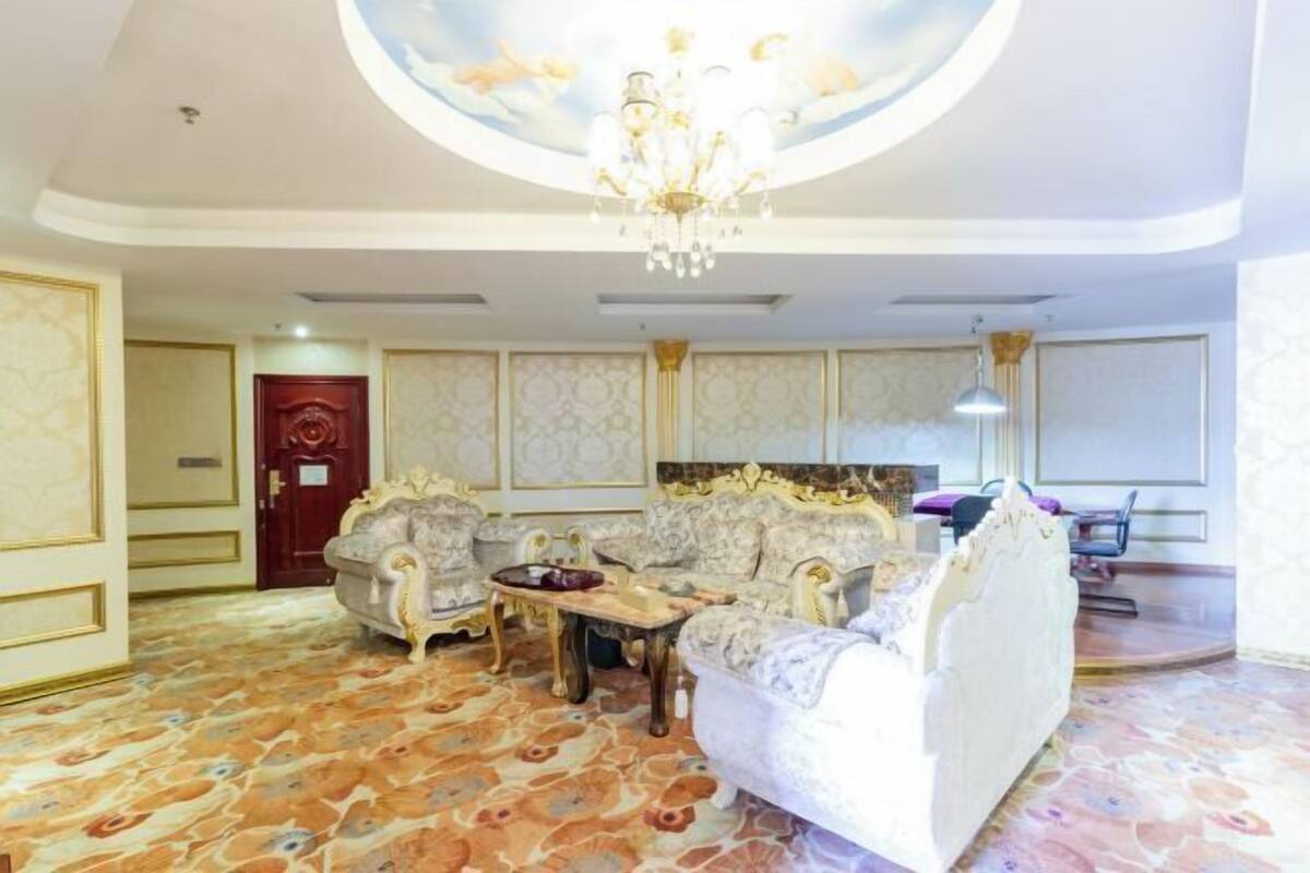 Uma sala de estar luxuosa com móveis ornamentados, um candelabro e piso estampado.